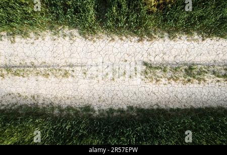 Drone scenery of secondary dry rural road crossing a farmland meadow ...