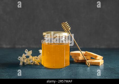 Jar of honey with flowers of acacia and crackers on dark background ...
