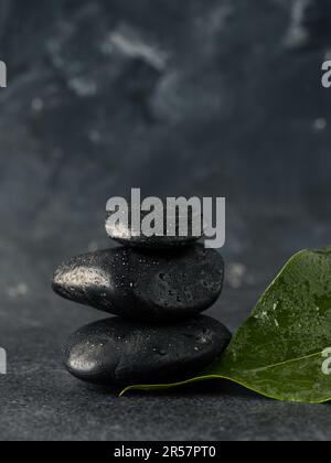 Stacked Massage stones with leaves on a dark stone table, spa ...