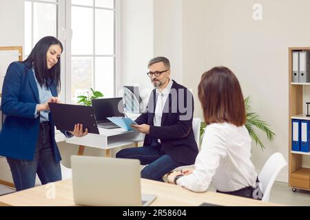 woman employee showing something to her colleagues on the monitor ...