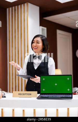 Receptionist having greenscreen on desk, welcoming guests at hotel and ...