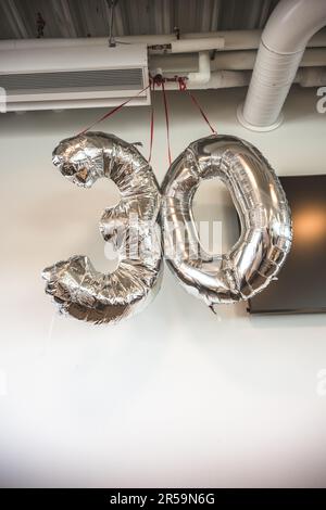 Silver balloons marking 30 year birthday in an office Stock Photo - Alamy