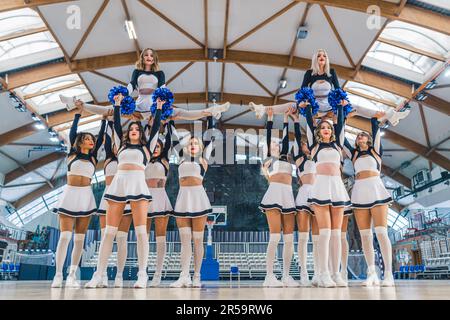 Cheerleader doing a split while other girls holding her up in the air ...