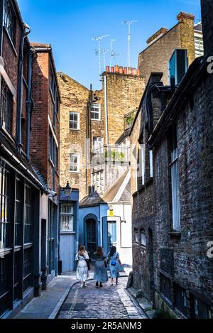 Three women walking in Newman Passage, a narrow alleyway in Fitzrovia ...