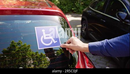 Driver Putting Wheelchair Sticker Sign On Car Vehicle Stock Photo - Alamy