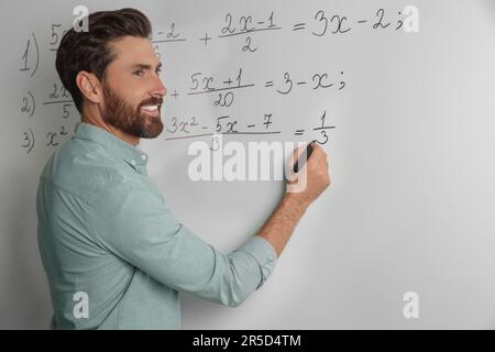 Happy teacher explaining mathematics at whiteboard in classroom Stock ...