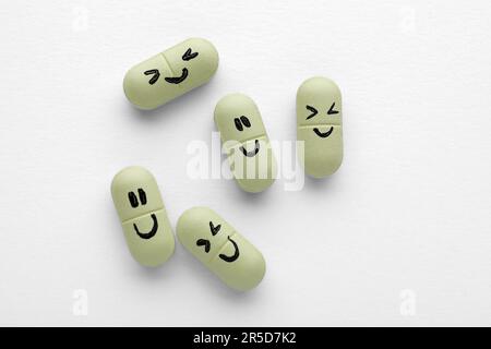 Antidepressant pills with emotional faces on white background, top view ...