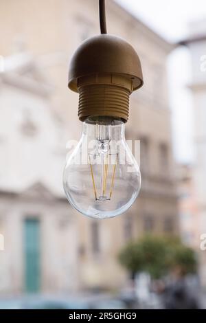 Street lamp with incandescent light bulb with blue sky energy waste ...