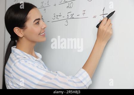 Happy teacher explaining mathematics at whiteboard in classroom Stock ...