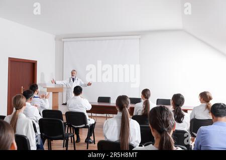 Senior doctor giving lecture to audience during medical conference in ...