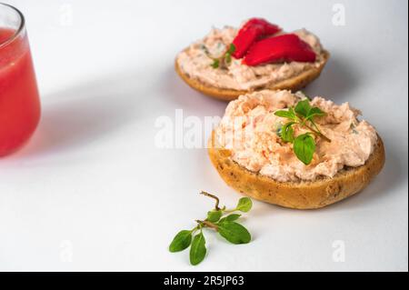 Two canapés with salmon spread and fresh cheese, part of glass of juice ...