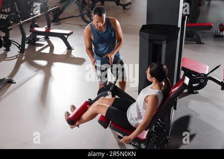 Trainer explaining woman how to do exercise properly in modern gym ...