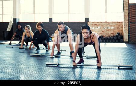 Raise the bar. a fitness group using steel bars in their session at the ...