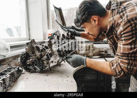 Workman disassembling car engine at the working table of the car ...