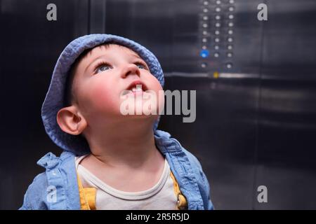 Happy baby rides in the elevator of an apartment building with buttons ...