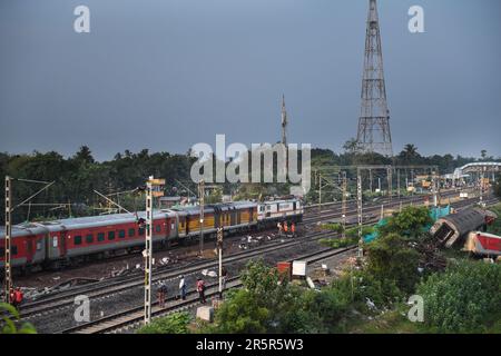Balasore. 5th June, 2023. A passenger train passes by the site of a ...