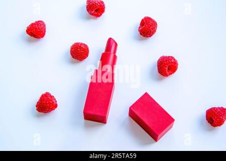 Bright red lipstick and ripe juicy raspberries on white background ...