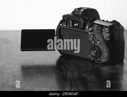 A grayscale shot of a professional DSLR camera on the table Stock Photo ...