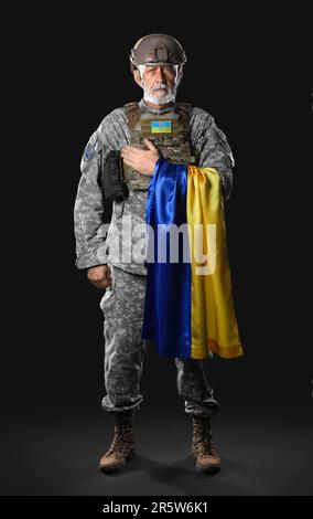 Mature soldier with flag of Ukraine on dark background, back view Stock ...