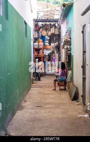 Woman dressed in a black hooded cloak is standing in a darkness next to ...
