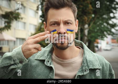 Angry man with drawings of Ukrainian flag against light grey background ...