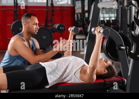 Trainer explaining woman how to do exercise properly in modern gym ...