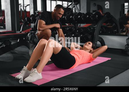 Trainer explaining woman how to do exercise properly in modern gym ...