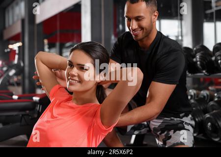 Trainer explaining woman how to do exercise properly in modern gym ...