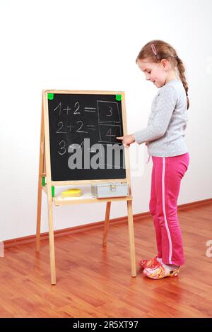 Cute girl doing the math on chalkborard Stock Photo - Alamy