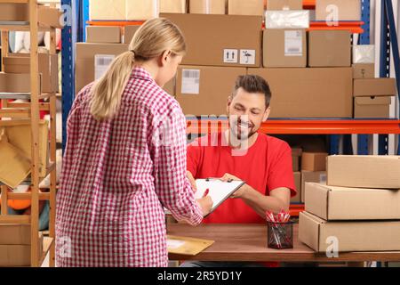 Woman signing papers for delivered parcel at post office Stock Photo ...