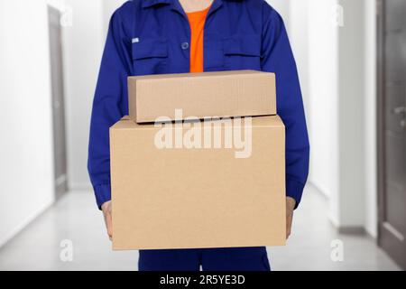 Courier with cardboard boxes in hallway, closeup Stock Photo - Alamy