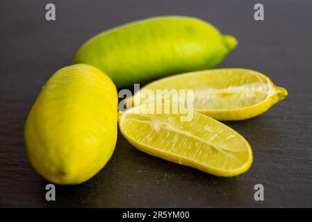Finger lime, cut in half, on a white surface Stock Photo - Alamy