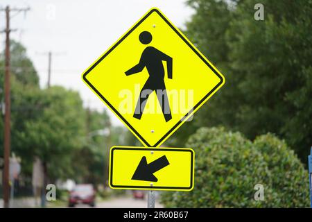 A bright yellow pedestrian crosswalk sign with a hula hoop drawn onto ...