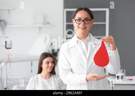 Female doctor with paper blood drop and heart in clinic Stock Photo - Alamy
