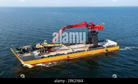 Yellow barge loaded with tracked harbour material handling cranes ...