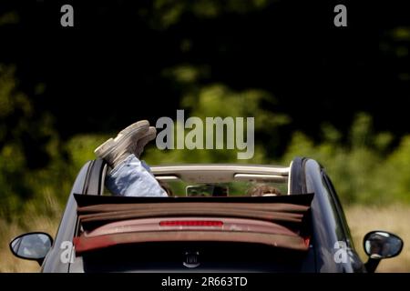 UTRECHT - Two shoes stick out of a convertible with an open roof. The ...