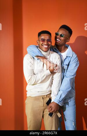 young and fashionable gay men smiling and looking away under ...