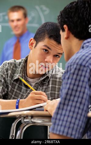 High school students collaborating on a project in a park, engaging in outdoor study together ...