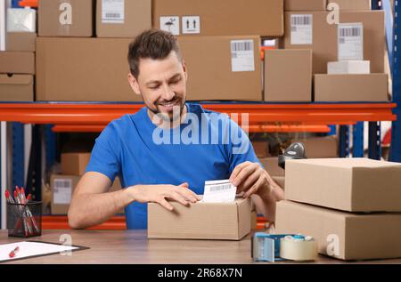 Post office worker sticking barcode on parcel at counter indoors Stock ...