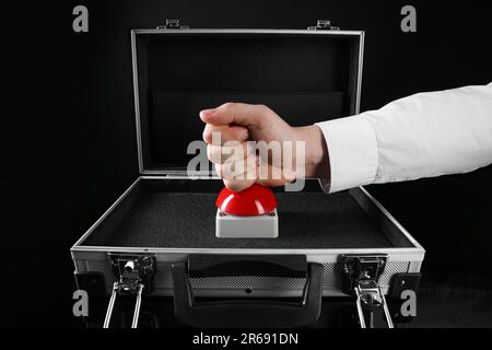 Man pressing red button of nuclear weapon at black background, closeup ...