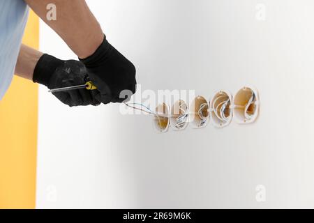 Handyman installing sockets in white wall, closeup Stock Photo - Alamy