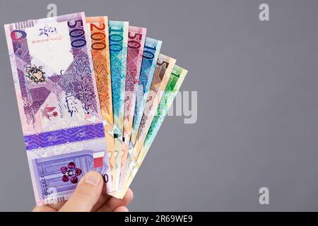 Qatari money - riyal in the hand on a gray background Stock Photo - Alamy