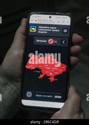 A smartphone in a woman's hands with the Official Map of Air Alerts in ...