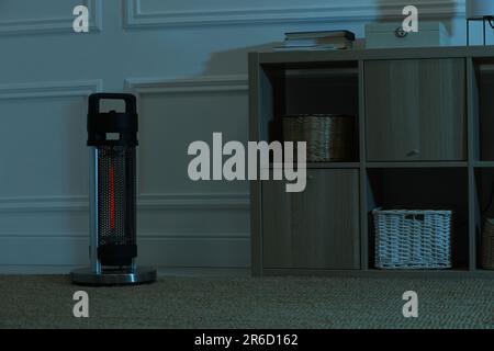 Electric infrared heater in dark living room at night Stock Photo - Alamy