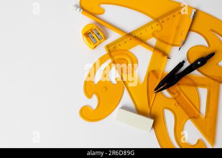Close up of yellow rulers, compass and sharpener on white background ...