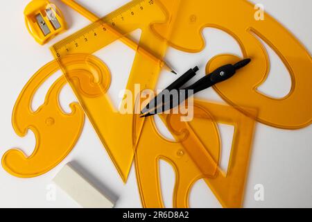 Close up of yellow rulers, compass and sharpener on white background ...
