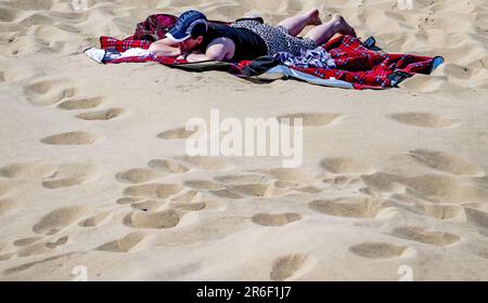 SCHEVENINGEN - Beachgoers enjoy the beautiful weather on the beach of ...