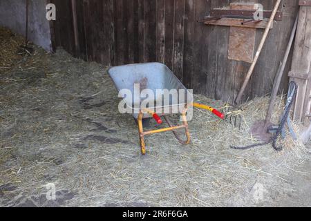 an old empty wheelbarrow stands in a barn Stock Photo - Alamy