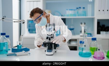 Middle age woman wearing scientist uniform using touchpad at laboratory ...