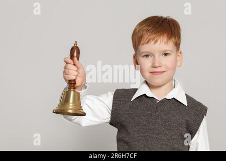 Pupil with school bell on light grey background Stock Photo - Alamy